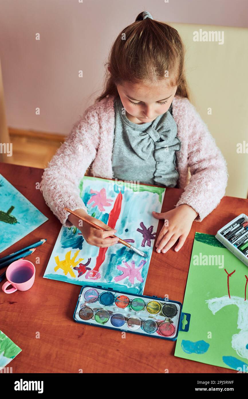Little girl preschooler painting a picture using colorful paints and ...