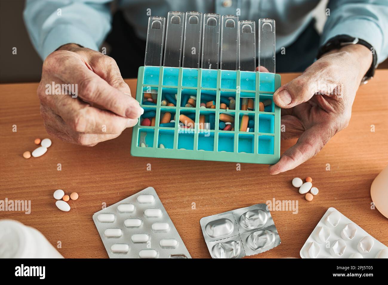 Senior man organizing his medication into pill dispenser. Senior man ...