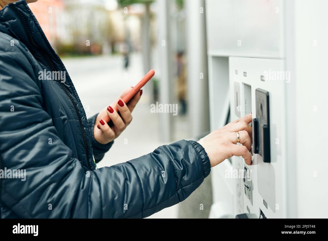 Woman buying ticket at ticket machine paying using mobile payment app ...