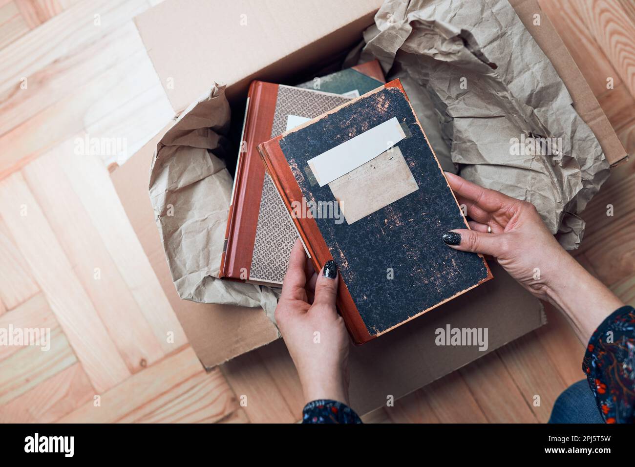 Woman taking books out of cardboox. Unpacking parcel. Female hands ...