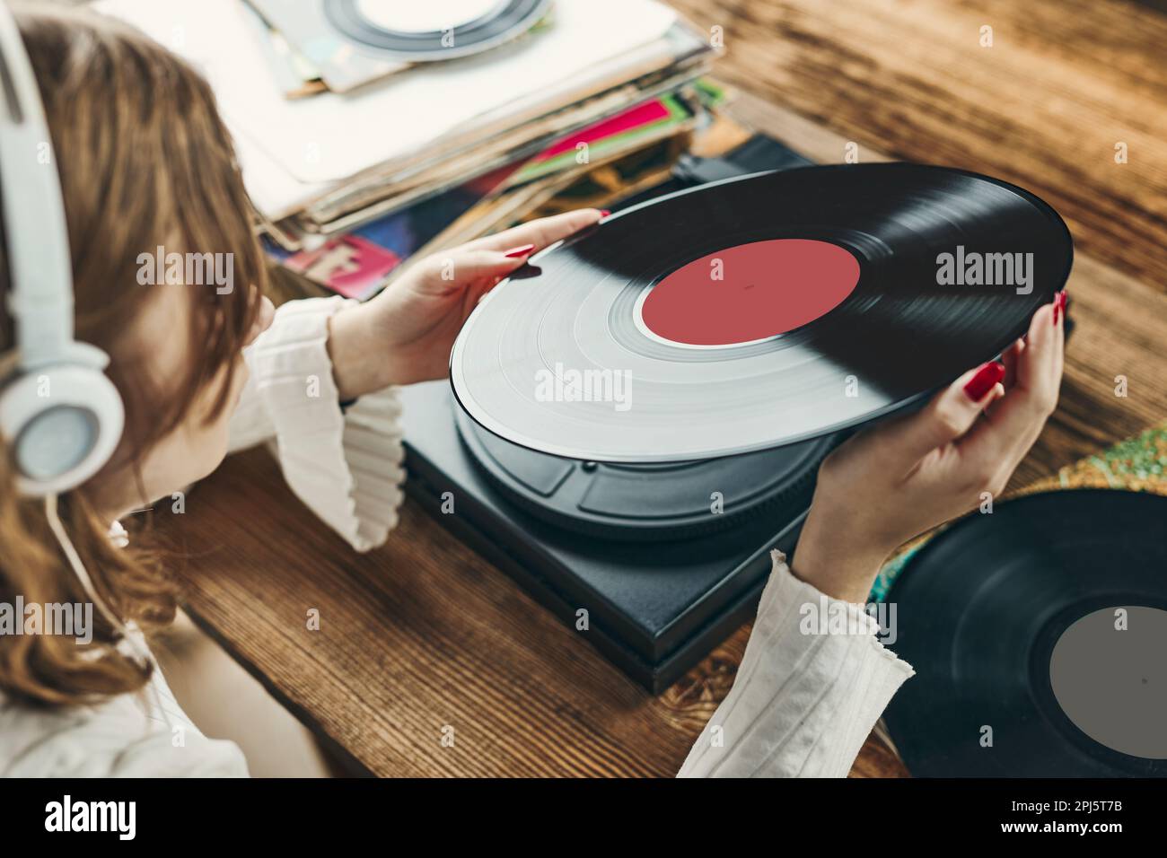 Young woman listening to music from vinyl record player. Playing music ...