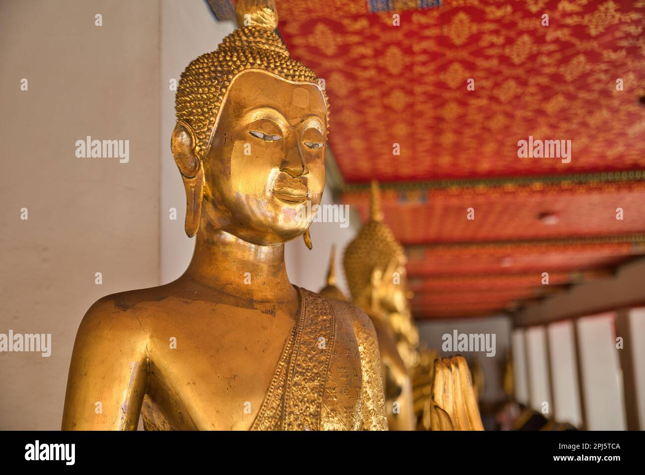 Golden Buddha figures diffuse along a corridor at Wat Pho temple in ...