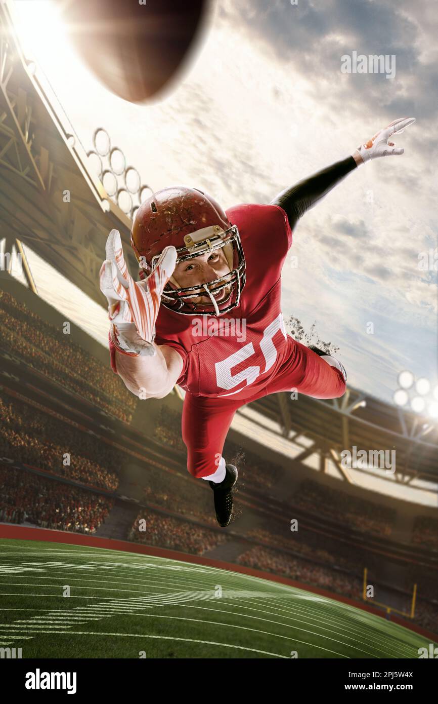 Wide angle view of american football player jumping and catching ball ...
