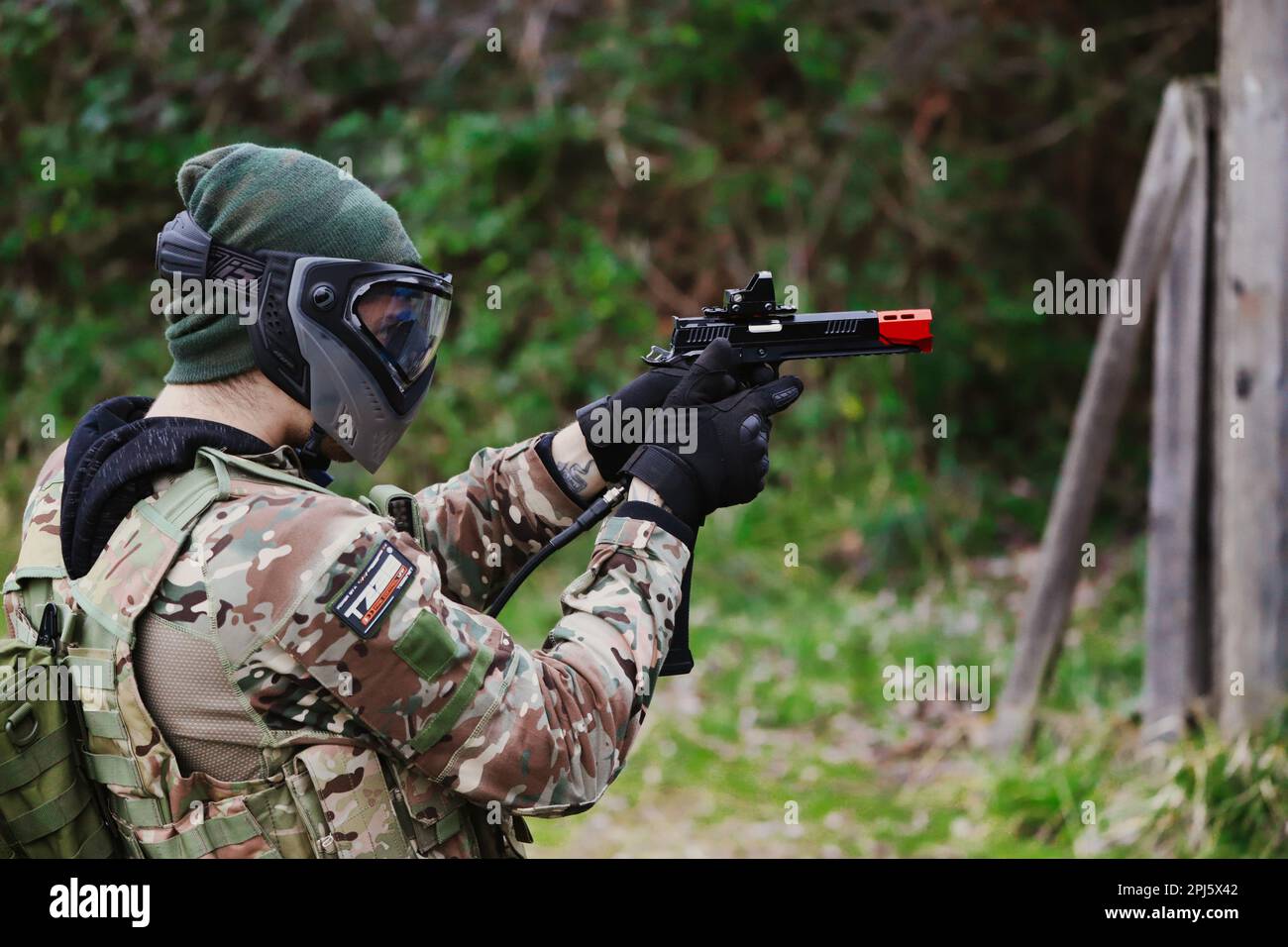 A person wearing a camouflage uniform aiming a rifle in the direction ...