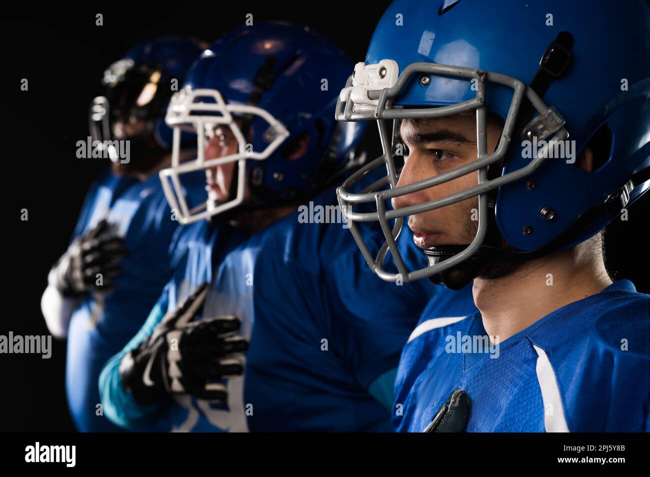 Portrait of three men in blue uniforms for American football with a ...