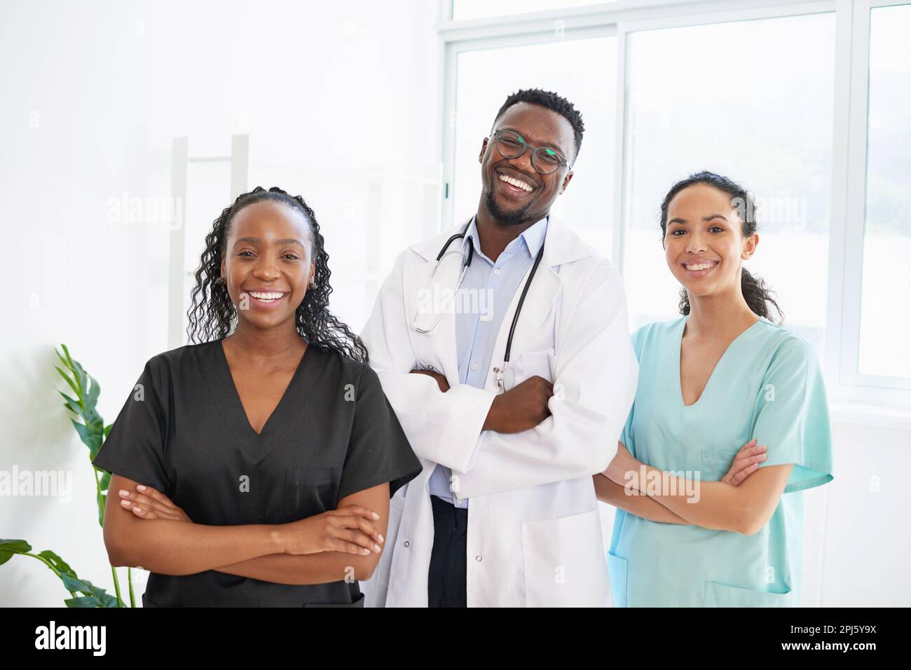 Three medical healthcare professionals stand in a row smiling arms ...