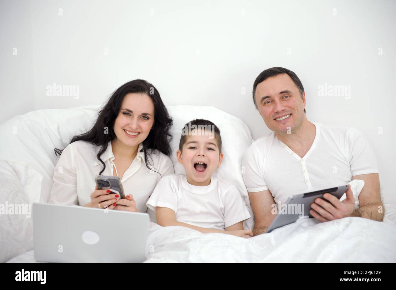 Happy family and digital technology. family parents and son lying on ...