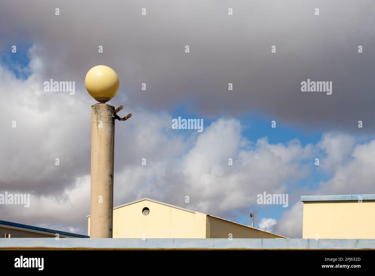 Roofs of a factory buildings. Street sphere lamp on a column.. Ball ...