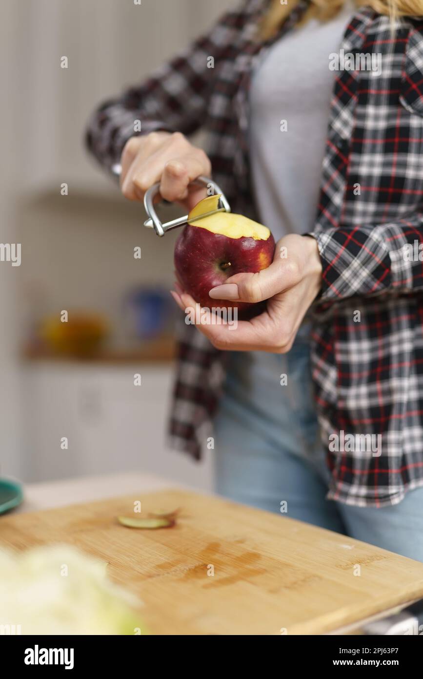 Female person peeling off red apple for lunch. Woman cooking healthy ...