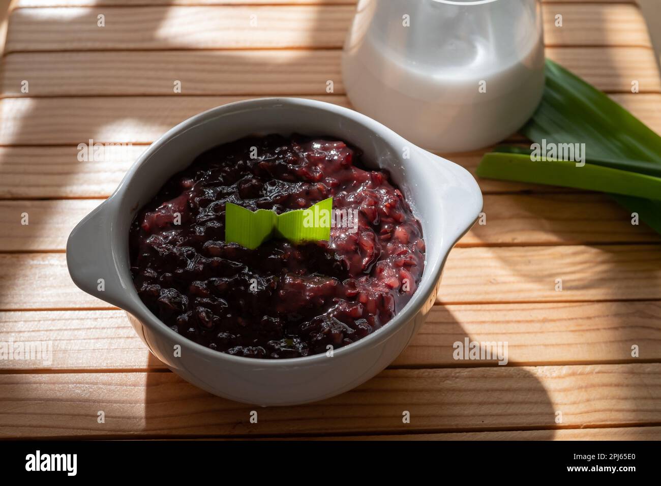 Black sticky rice porridge with coconut milk sauce served in a white ...