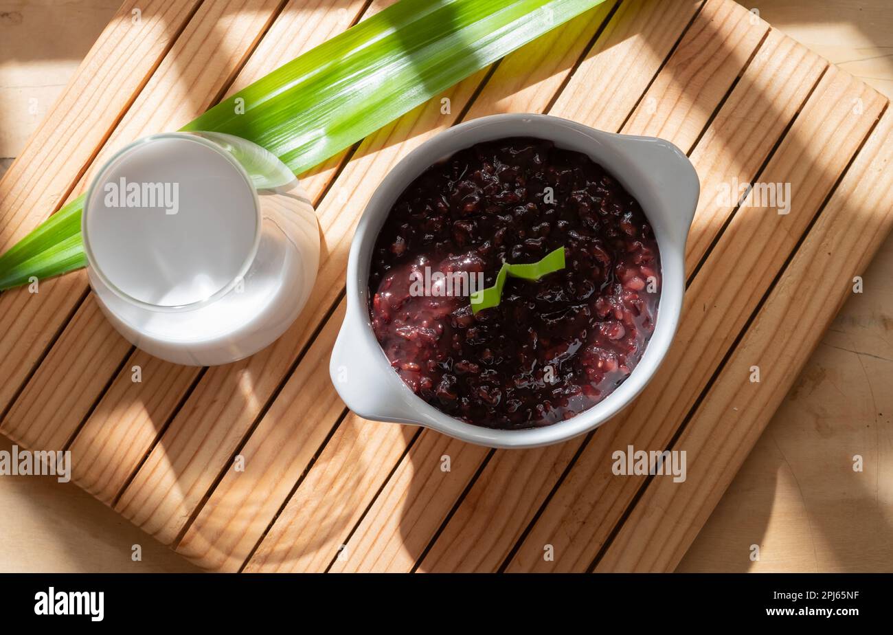 Black sticky rice porridge with coconut milk sauce served in a white ...