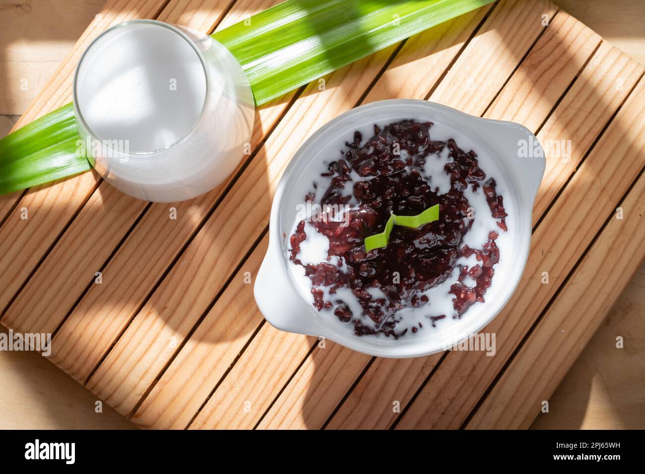 Black sticky rice porridge with coconut milk sauce served in a white ...