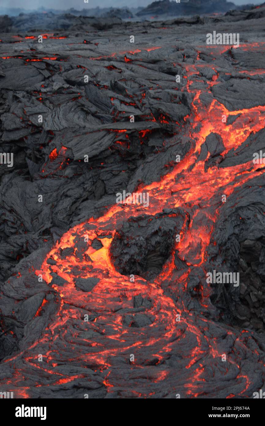 A volcanic eruption with glowing orange lava flow surrounded by a pool ...