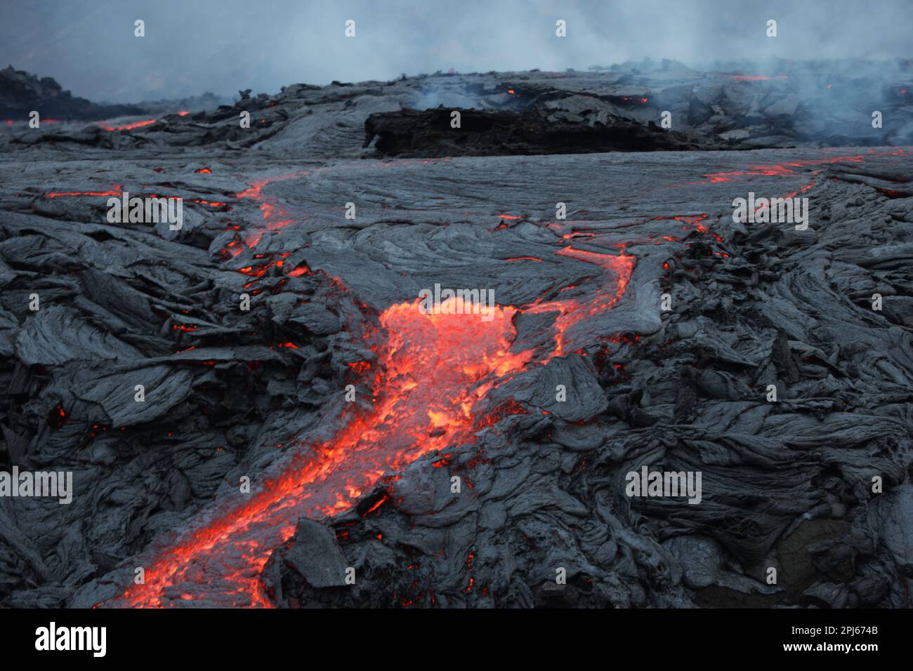 A volcanic eruption with glowing orange lava flow surrounded by a pool ...