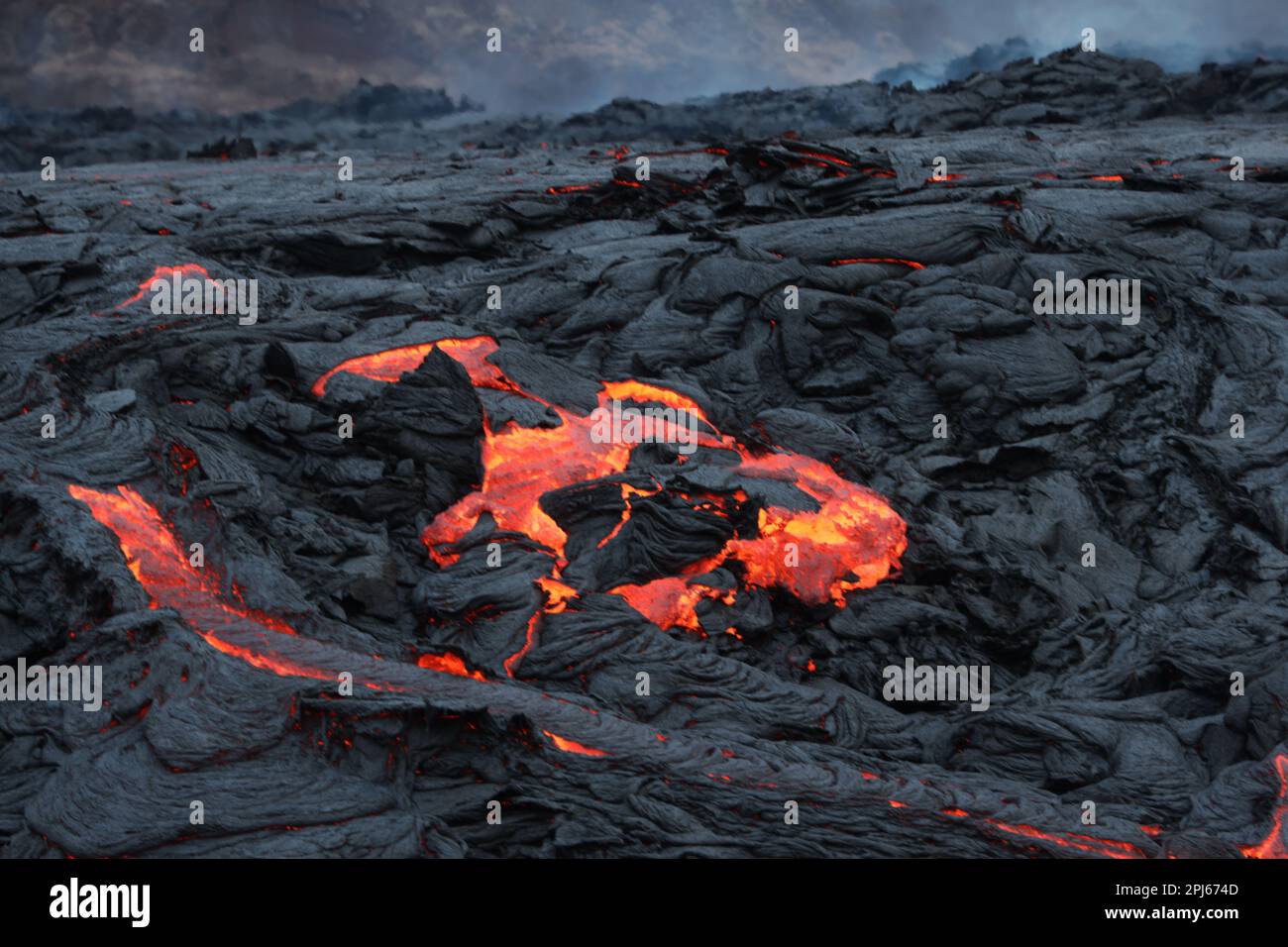 A volcanic eruption with glowing orange lava flow surrounded by a pool ...