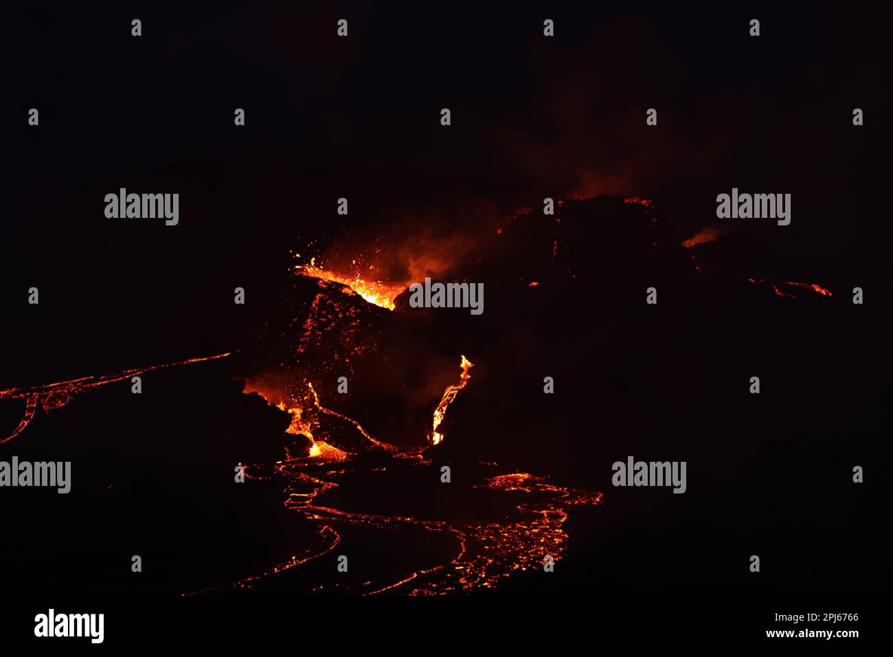 A volcanic eruption with glowing orange lava flow surrounded by a pool ...