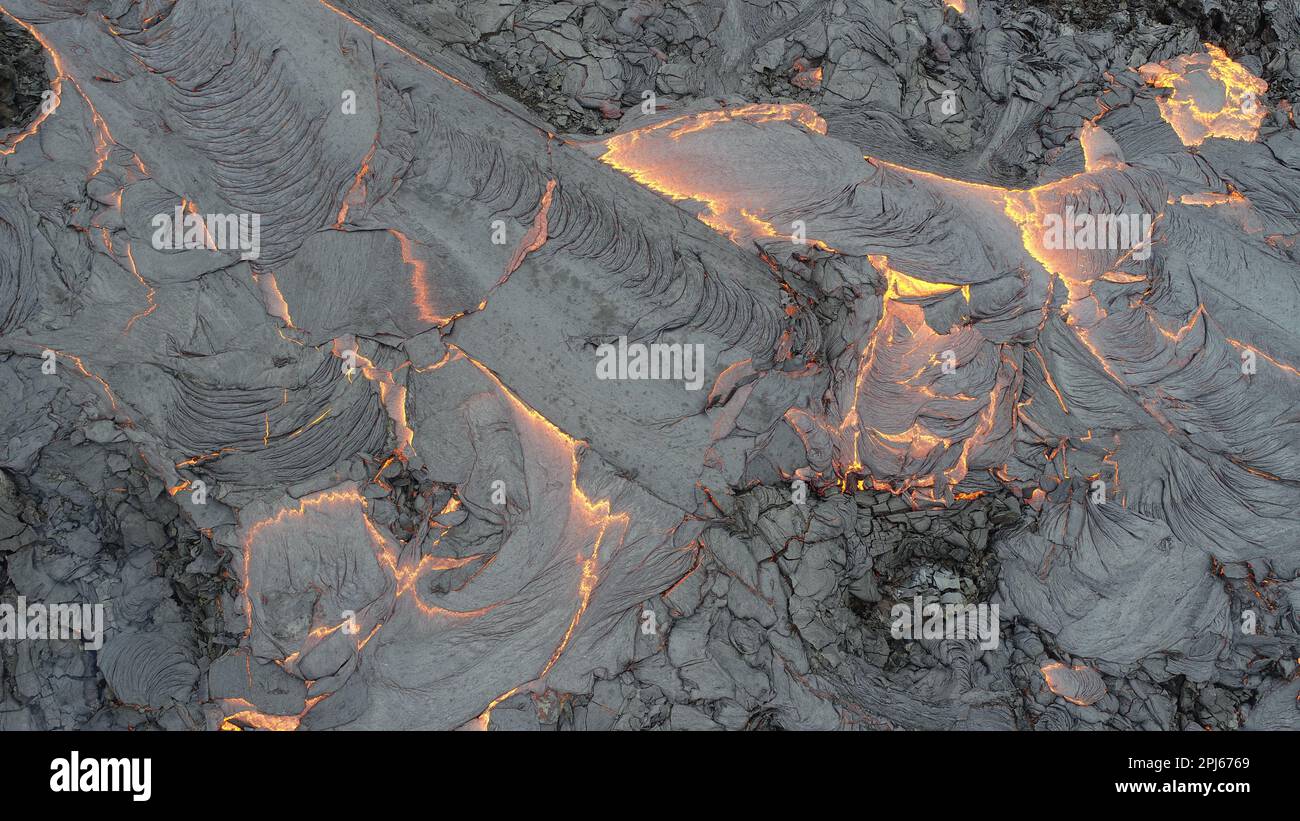 A volcanic eruption with glowing orange lava flow surrounded by a pool ...