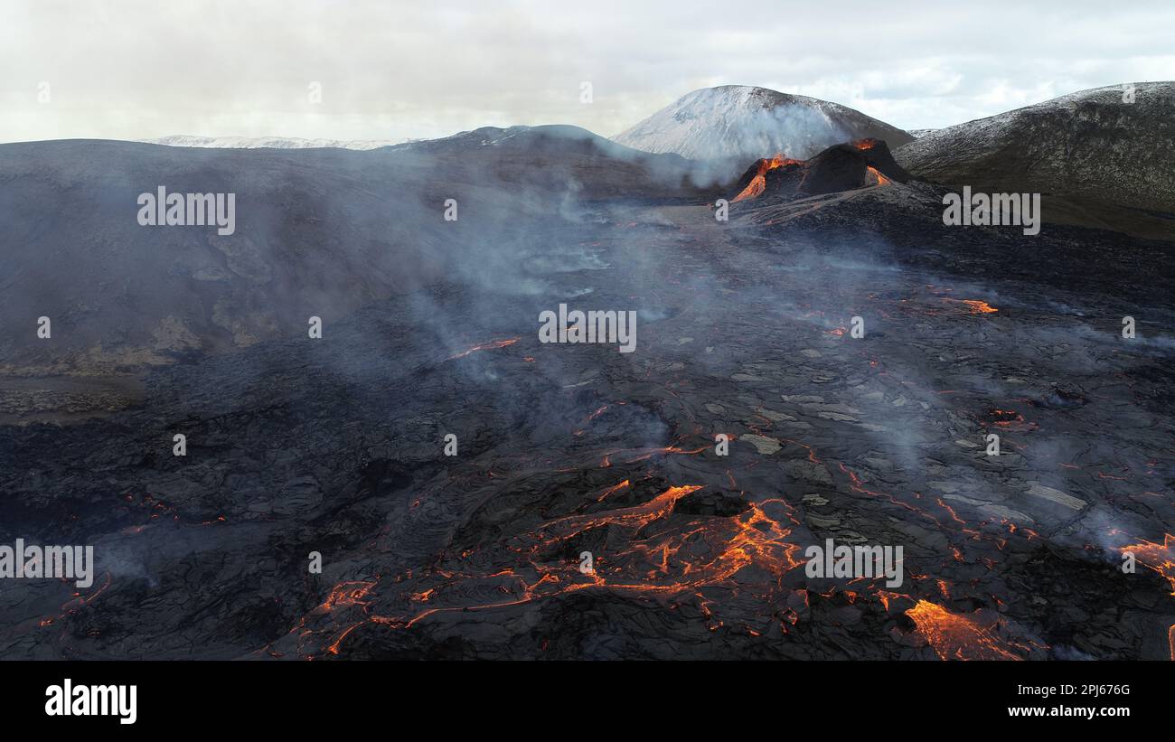 A volcanic eruption with glowing orange lava flow surrounded by a pool ...
