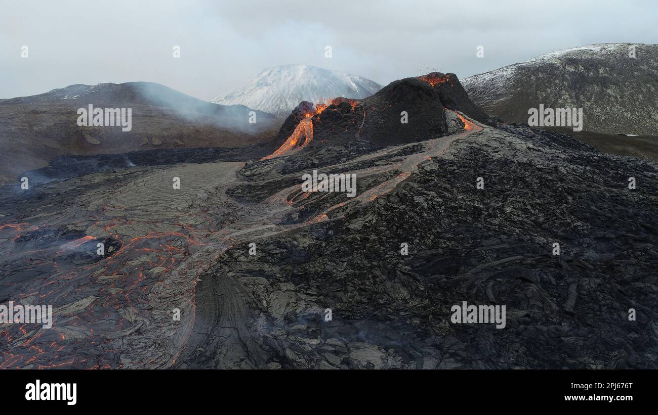 A volcanic eruption with glowing orange lava flow surrounded by a pool ...