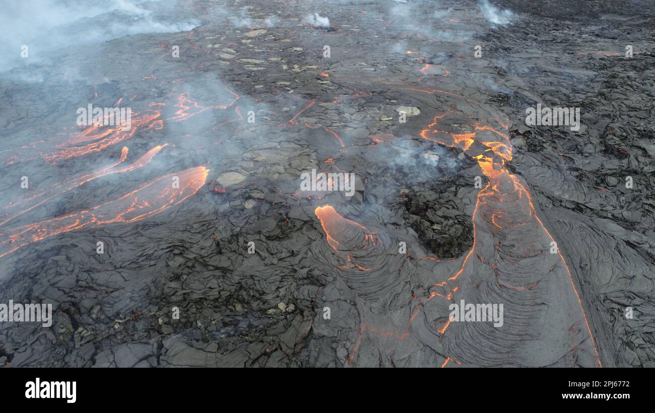 A volcanic eruption with glowing orange lava flow surrounded by a pool ...
