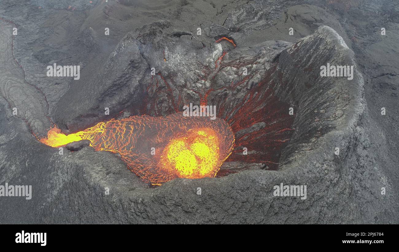 A volcanic eruption with glowing orange lava flow surrounded by a pool ...