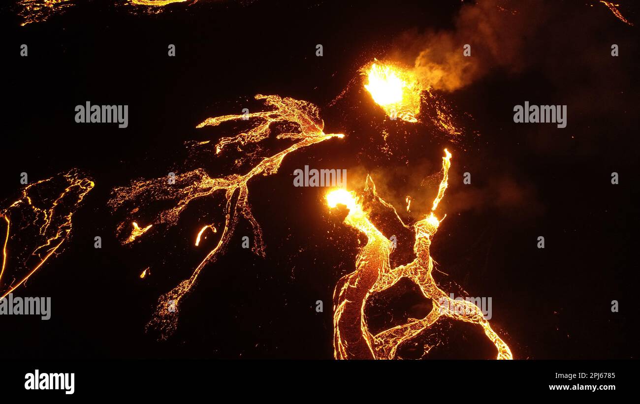 A volcanic eruption with glowing orange lava flow surrounded by a pool ...