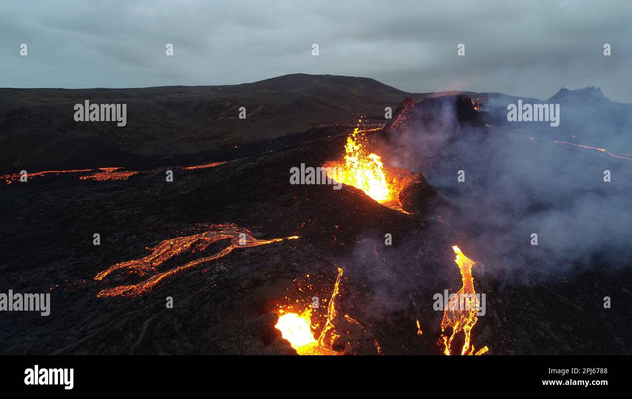 A volcanic eruption with glowing orange lava flow surrounded by a pool ...
