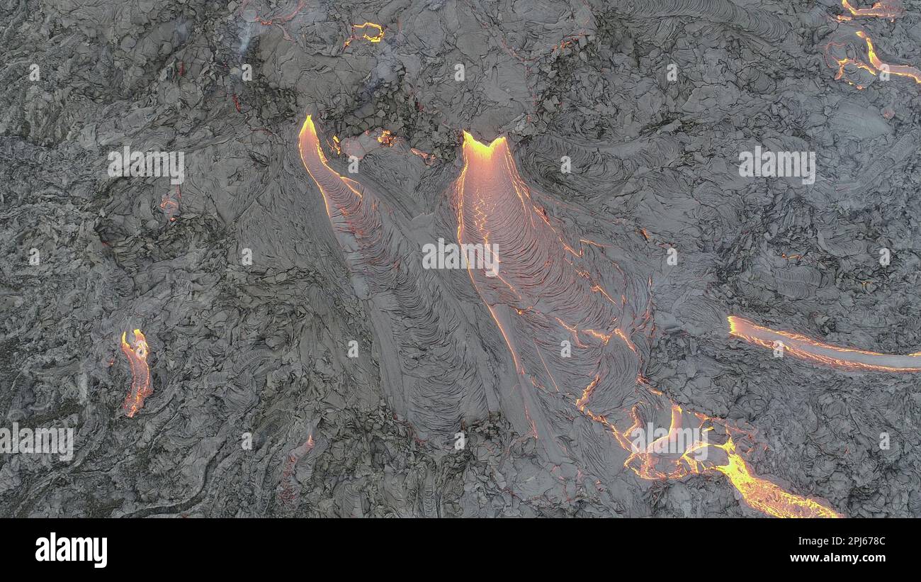 A volcanic eruption with glowing orange lava flow surrounded by a pool ...