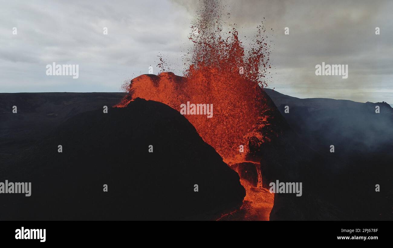 A volcanic eruption with glowing orange lava flow surrounded by a pool ...