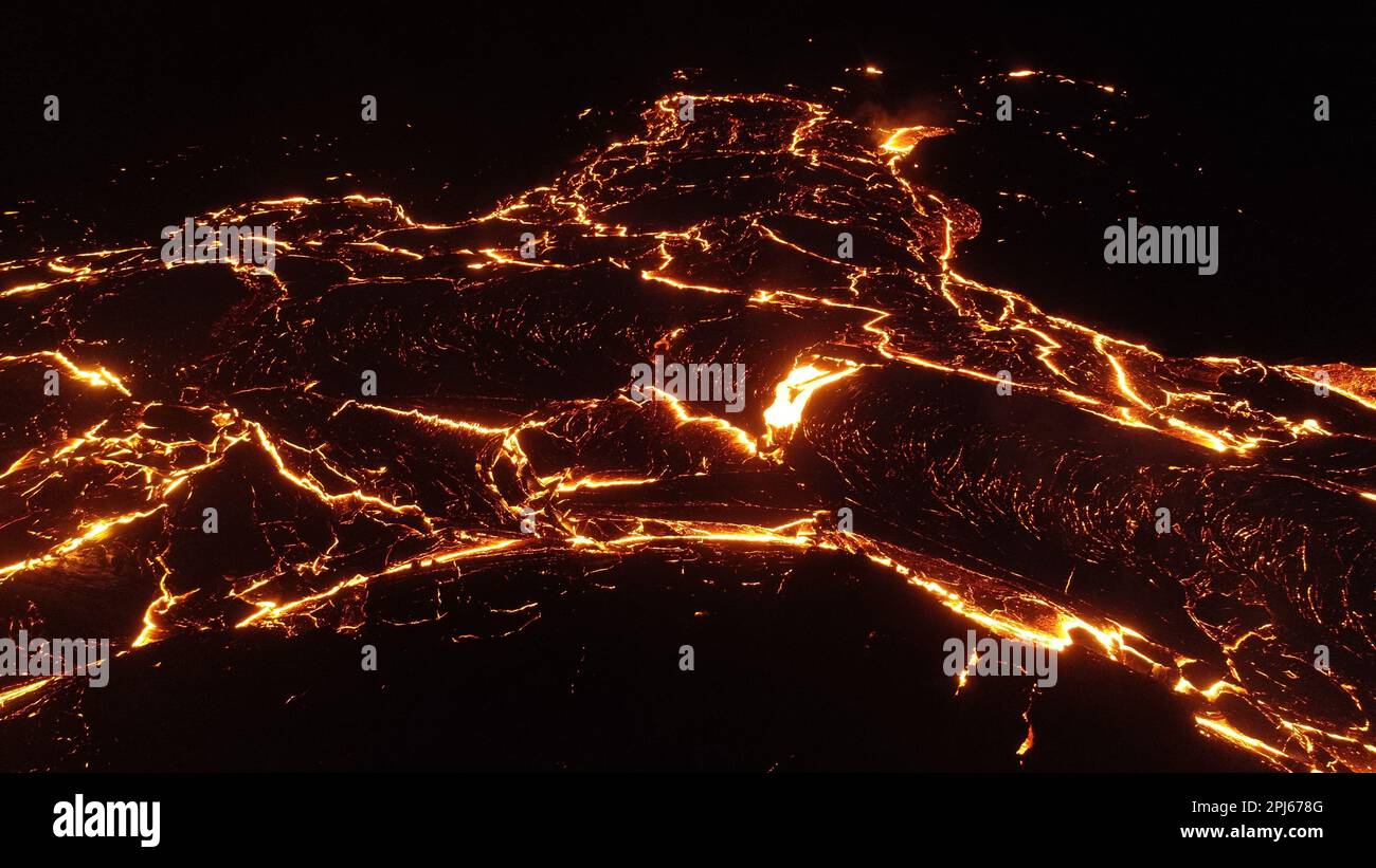 A volcanic eruption with glowing orange lava flow surrounded by a pool ...
