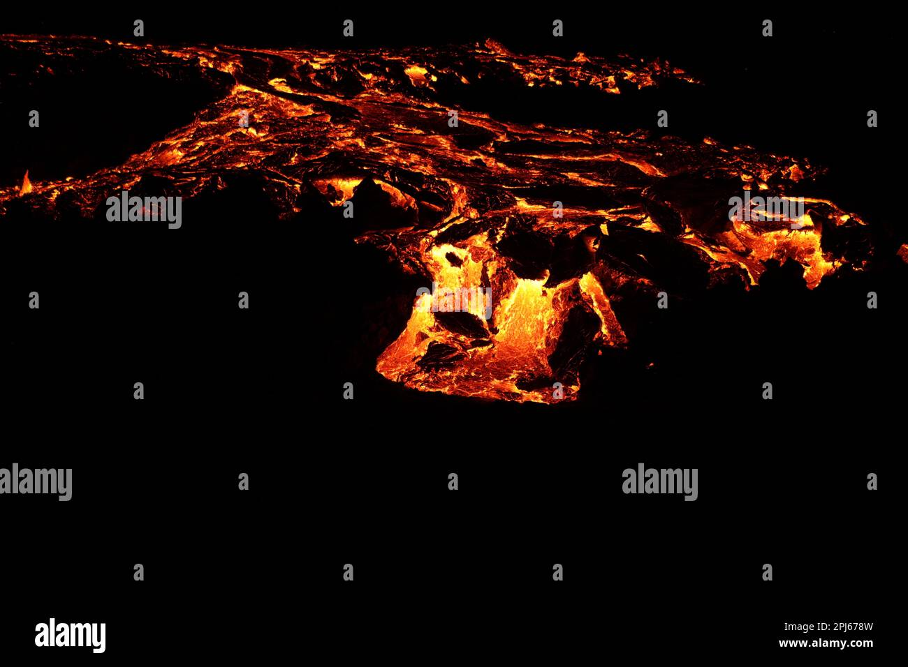 A volcanic eruption with glowing orange lava flow surrounded by a pool ...