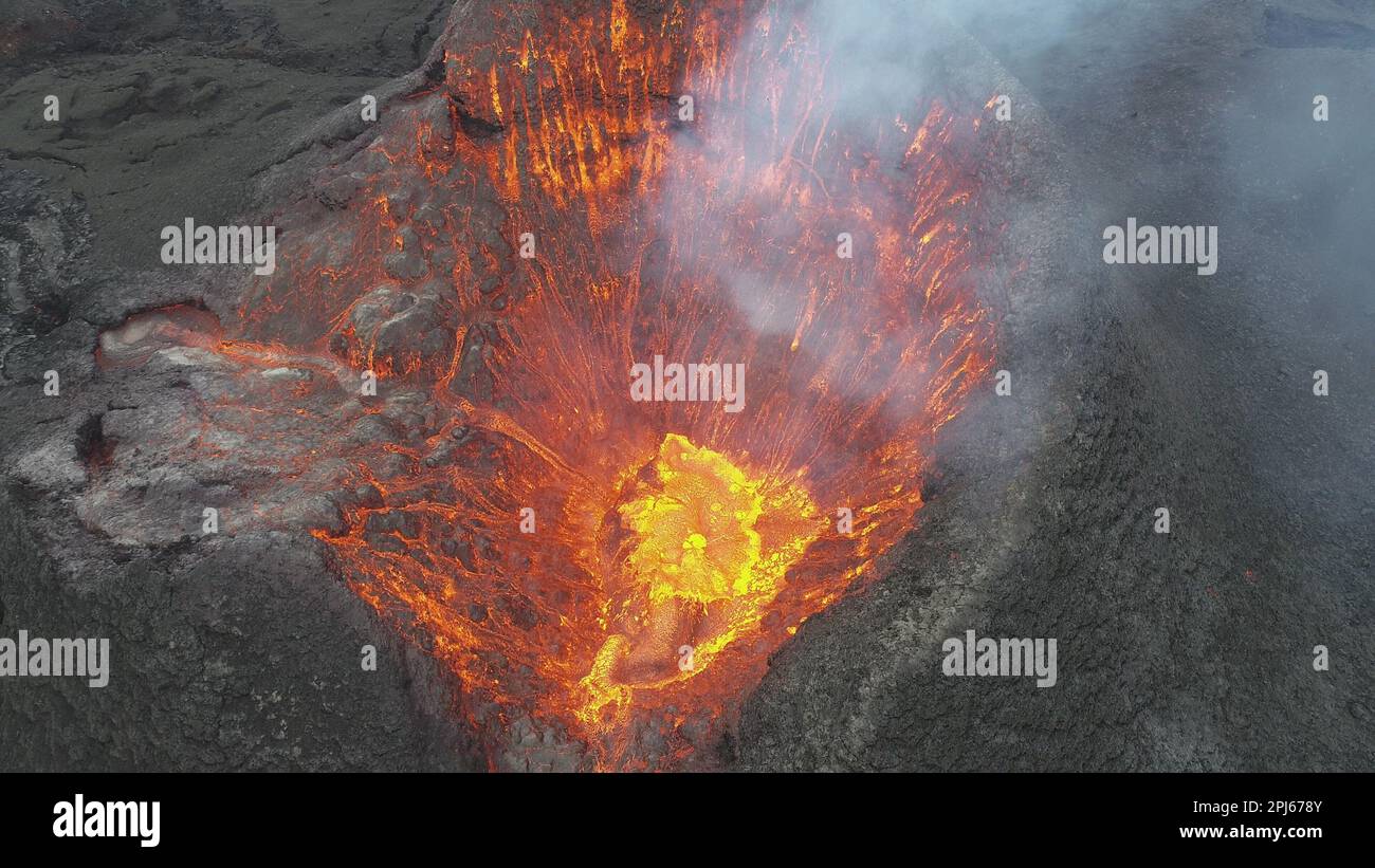 A volcanic eruption with glowing orange lava flow surrounded by a pool ...