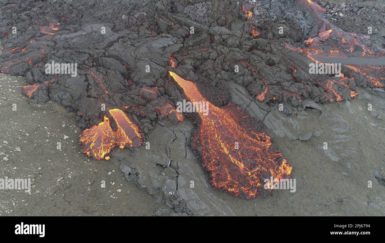 A volcanic eruption with glowing orange lava flow surrounded by a pool ...
