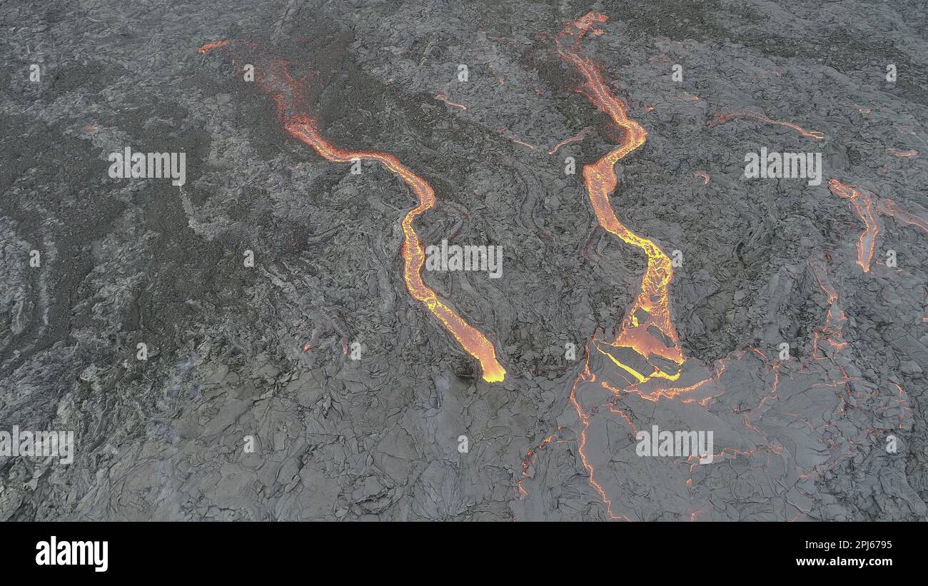 A volcanic eruption with glowing orange lava flow surrounded by a pool ...
