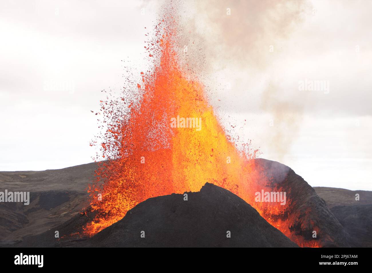 A volcanic eruption with glowing orange lava flow surrounded by a pool ...