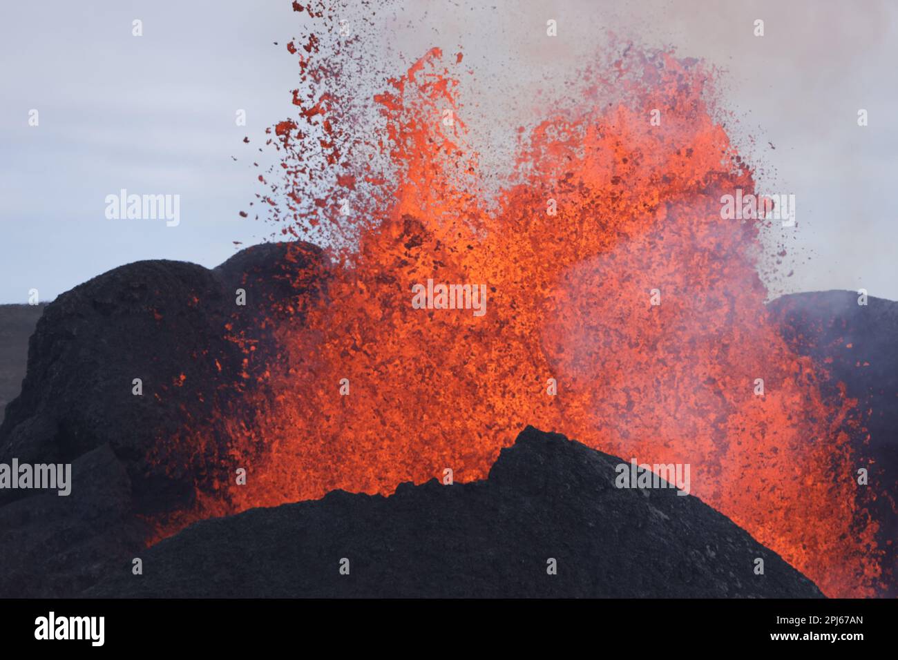 A volcanic eruption with glowing orange lava flow surrounded by a pool ...