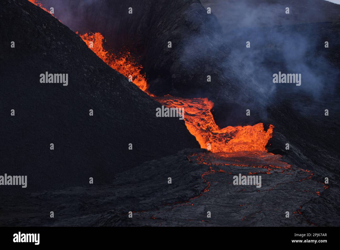 A volcanic eruption with glowing orange lava flow surrounded by a pool ...