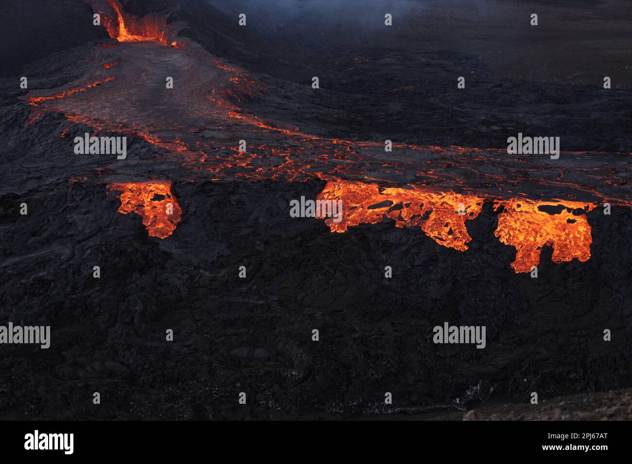 A volcanic eruption with glowing orange lava flow surrounded by a pool ...