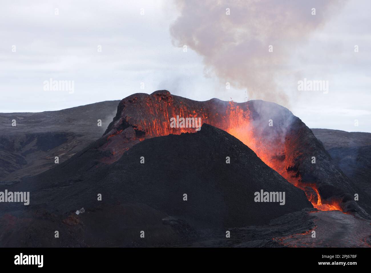 A volcanic eruption with glowing orange lava flow surrounded by a pool ...
