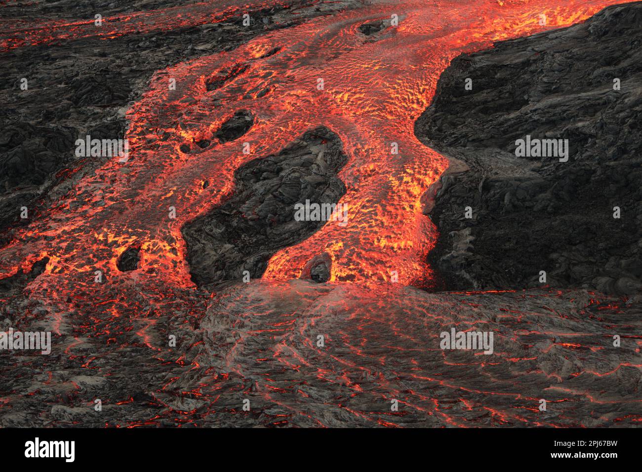 A volcanic eruption with glowing orange lava flow surrounded by a pool ...