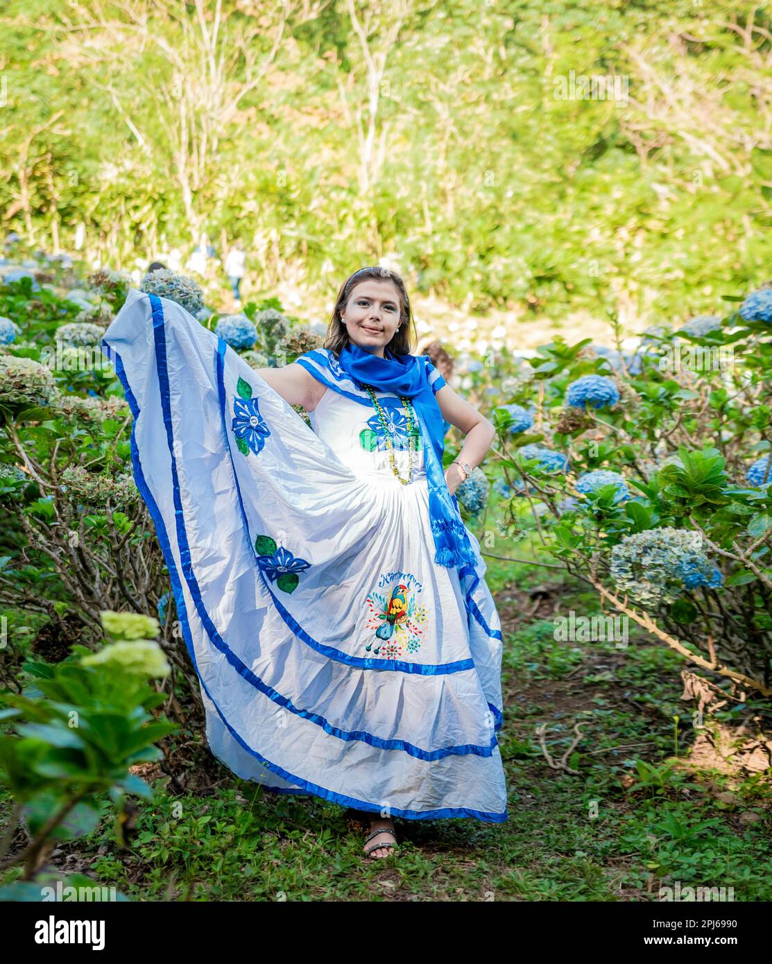 Smiling woman in national folk costume in a field surrounded by flowers ...