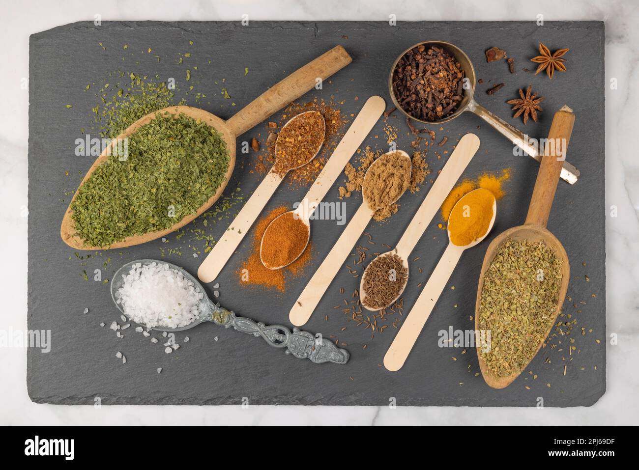 Various spices on different spoons, oregano, sea salt, paprika, cloves ...