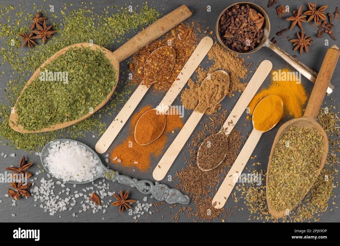 Various spices on different spoons, oregano, sea salt, paprika, cloves ...