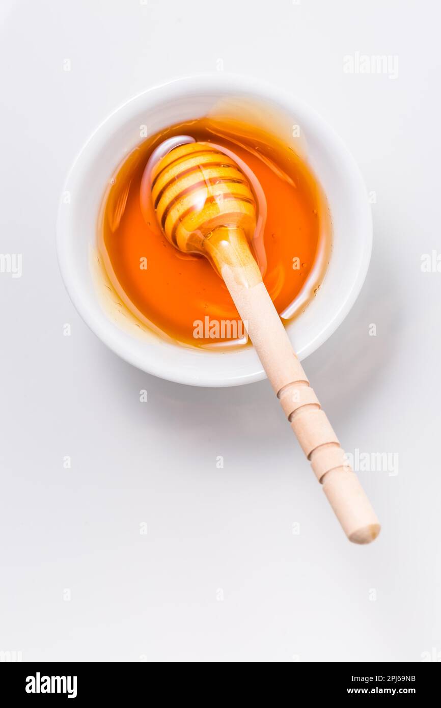 Honey with wooden honey dipper on white background Stock Photo - Alamy