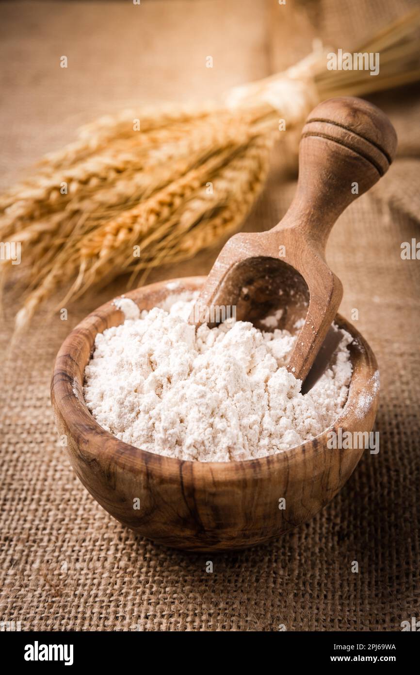 Flour in wooden bowl with grain on burlap background Stock Photo - Alamy