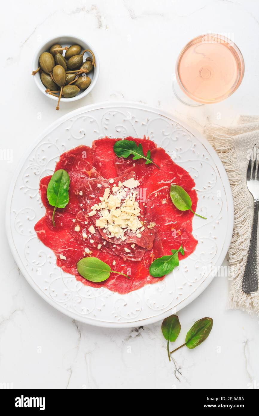 Beef carpaccio with capers and parmesan cheese as appetizer with rose ...