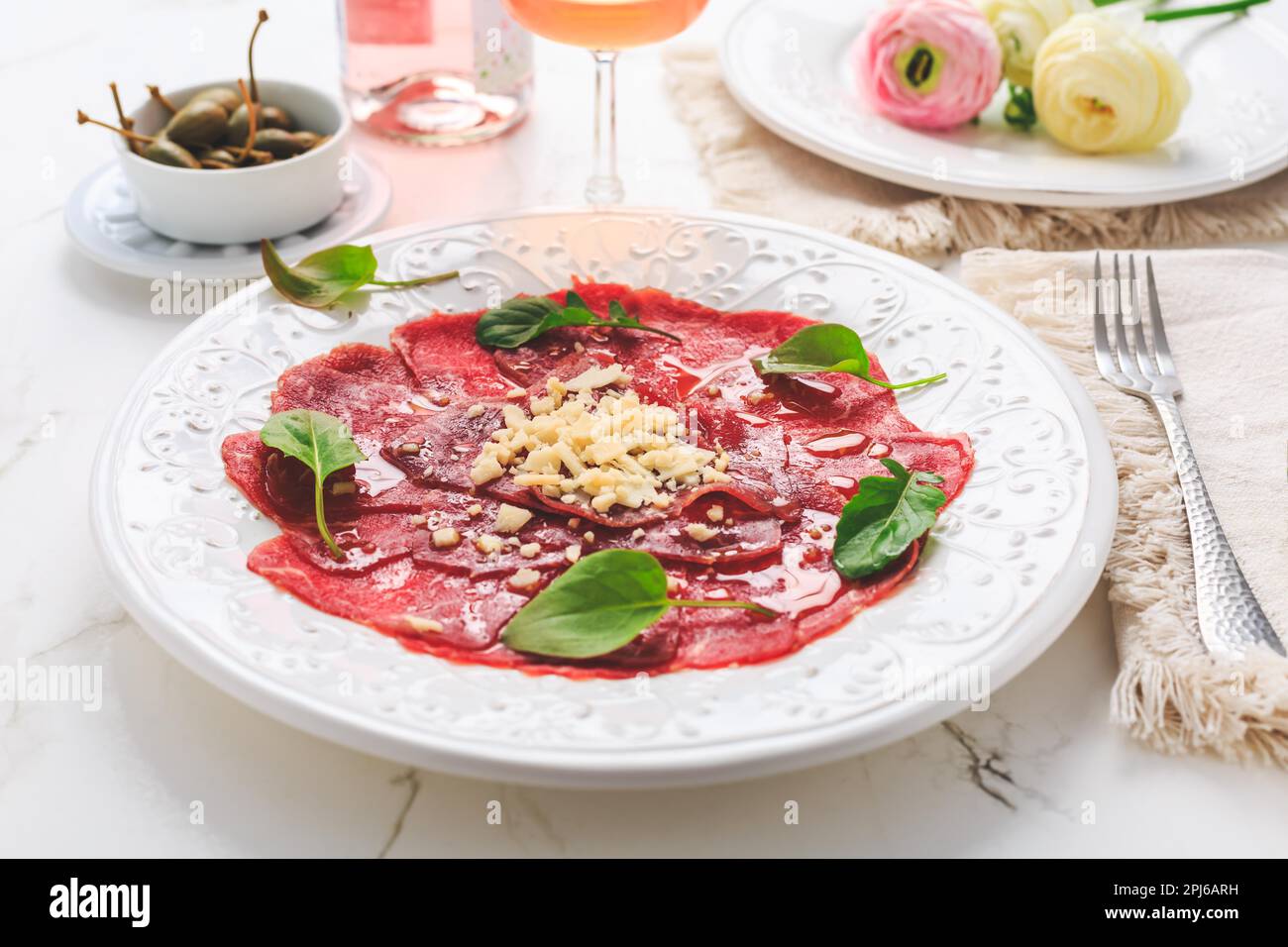 Beef carpaccio with capers and parmesan cheese as appetizer with rose ...