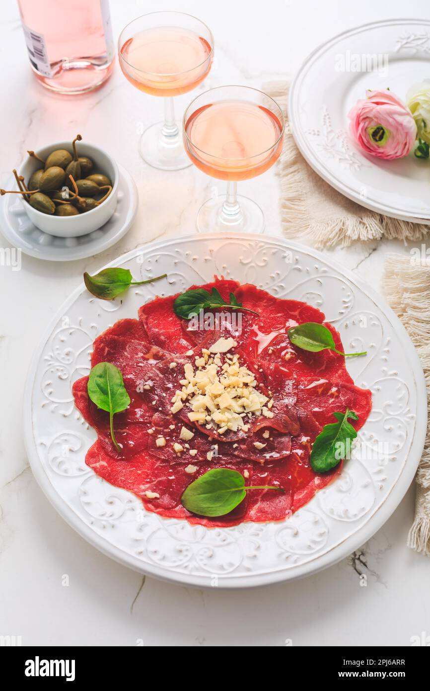 Beef carpaccio with capers and parmesan cheese as appetizer with rose ...