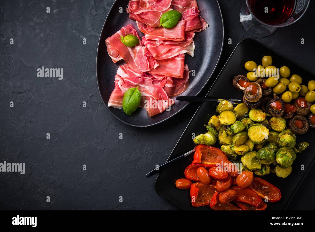 Assortment of appetizers and tapas with red wine on black background ...