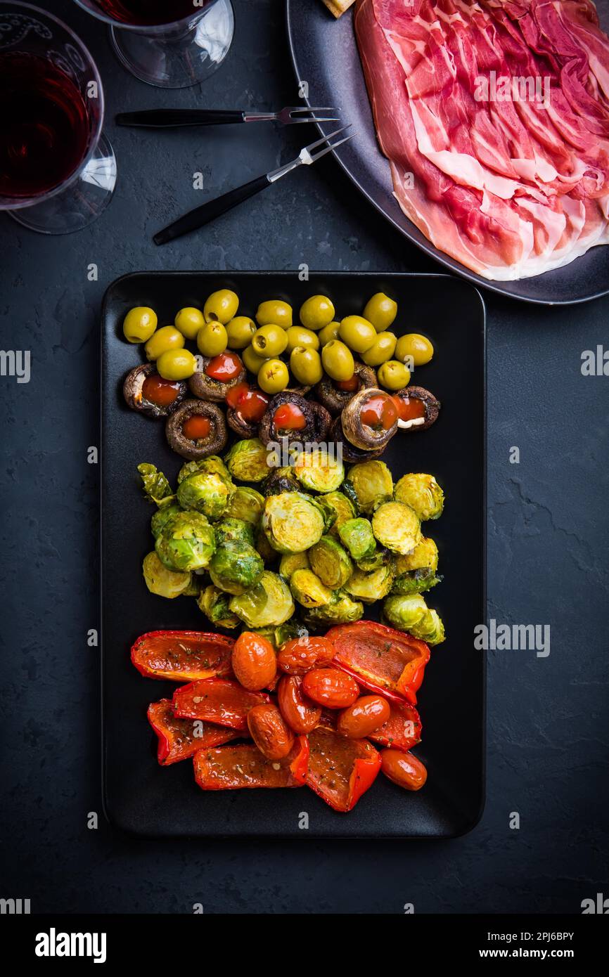 Assortment of appetizers and tapas with red wine on black background ...